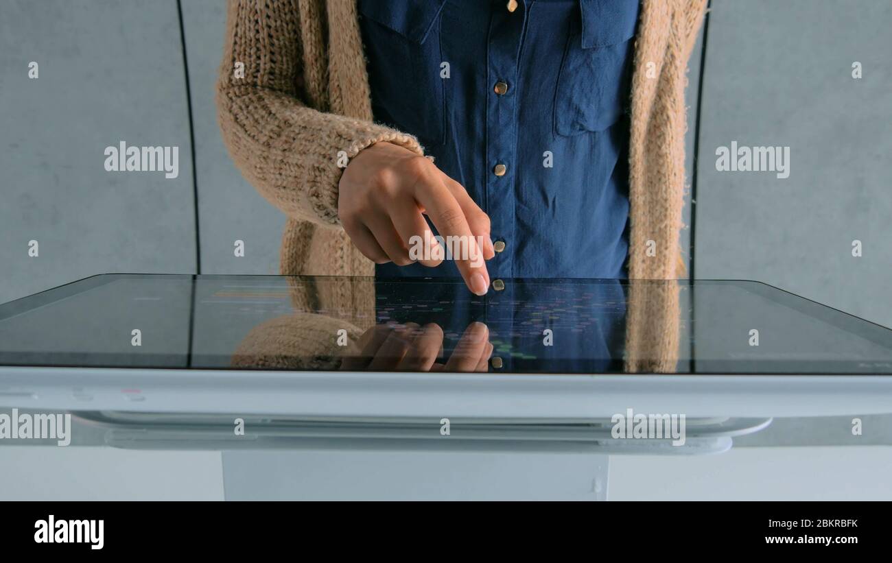 Woman using interactive touchscreen display at urban exhibition ...
