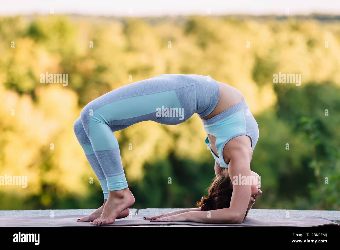 Pretty Woman Doing Yoga Exercises In The Park On Blurry Background
