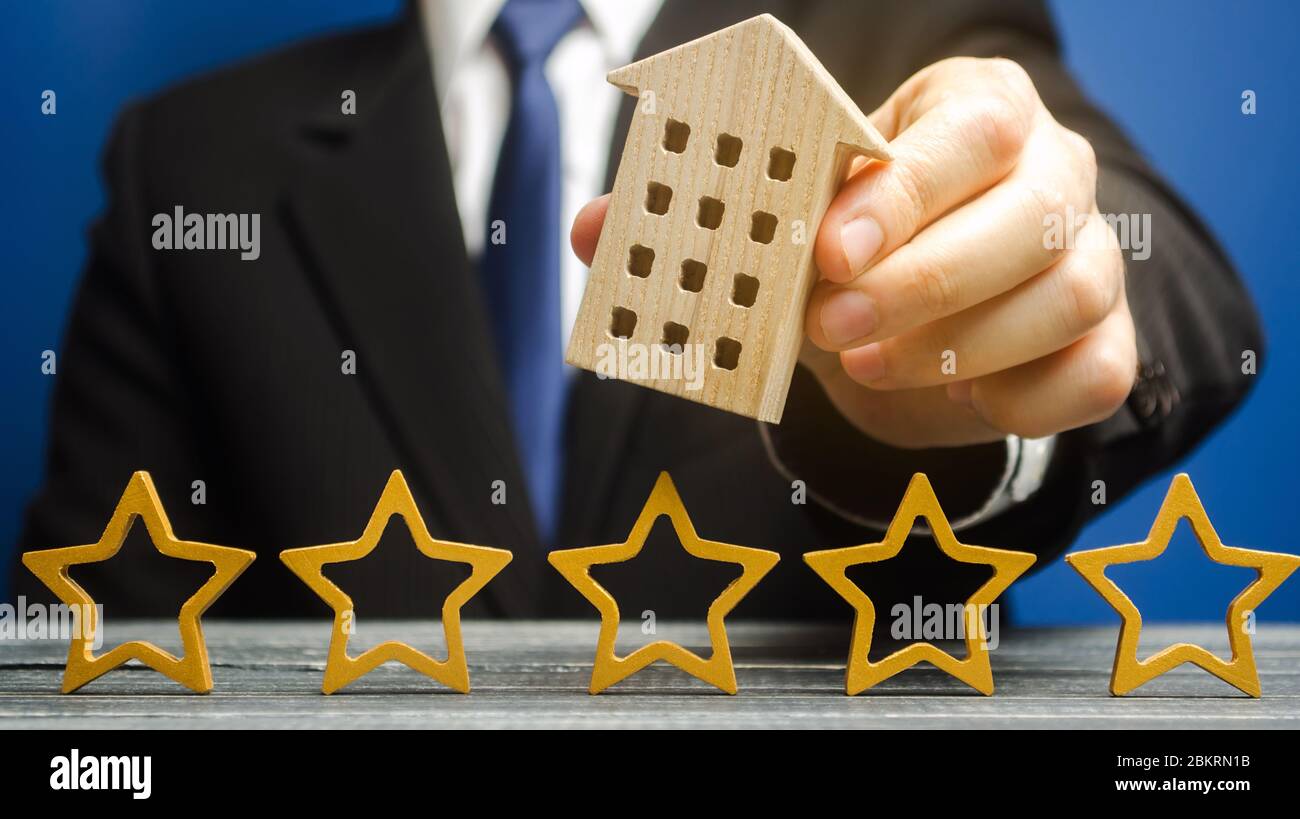 Five stars and a wooden house in the hands of a businessman. The ...