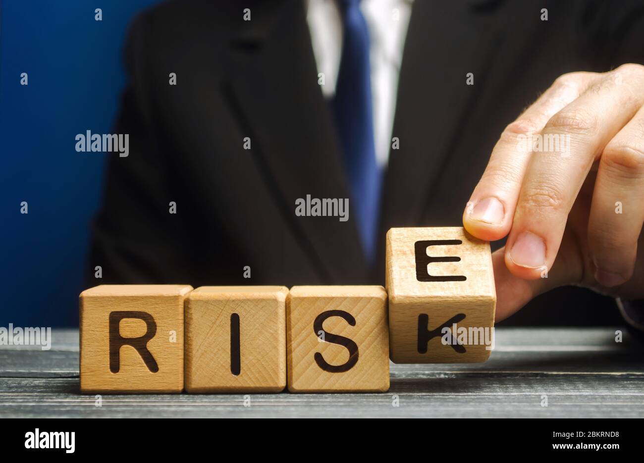 Businessman changes wooden blocks with the words Risk and Rise ...