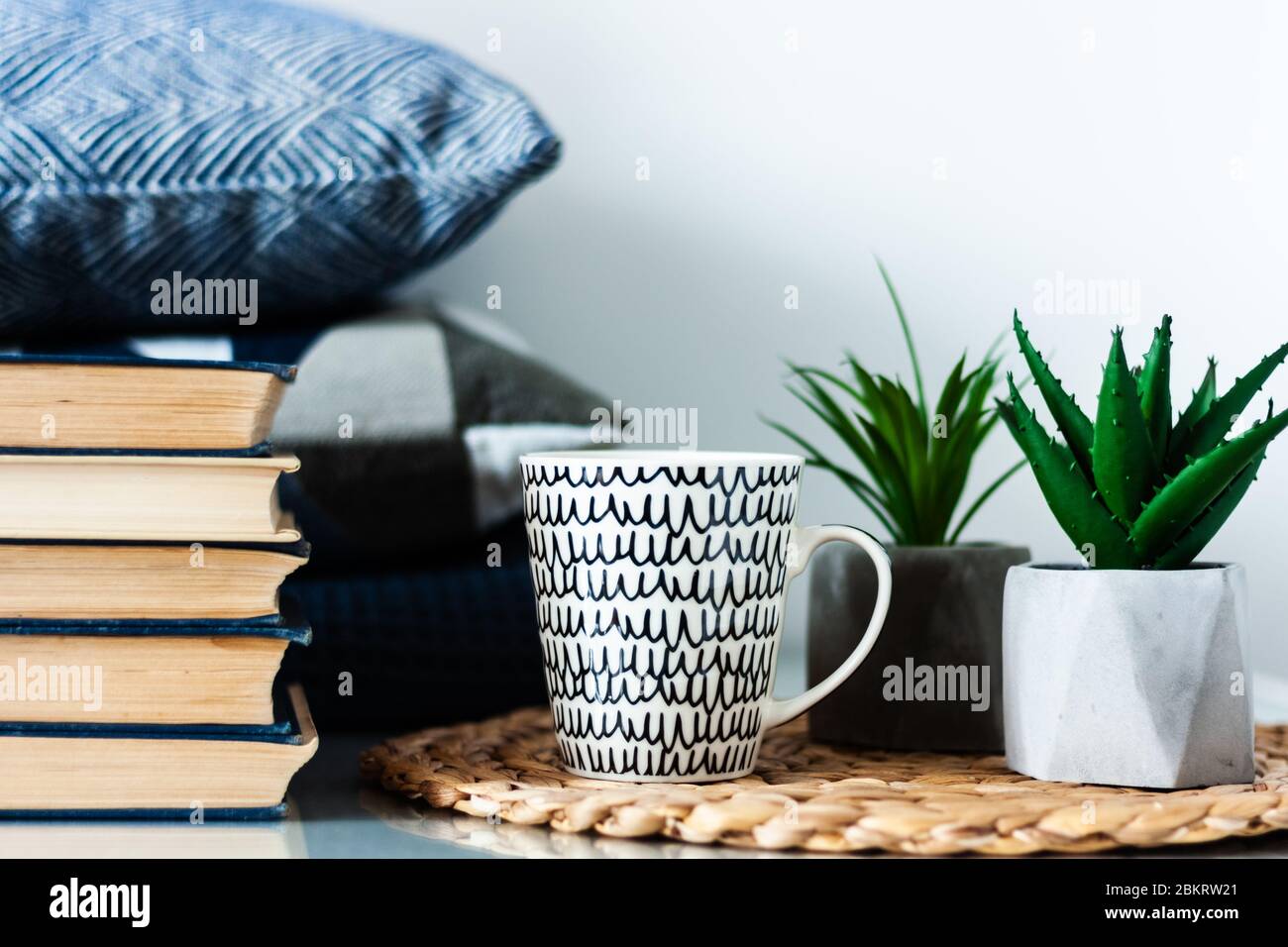 Cozy home interior decor: white and black cup, stack of books, plants ...