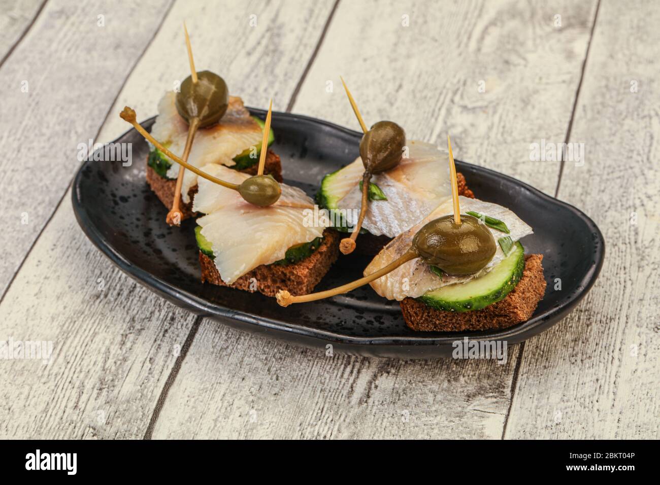 Herring fillet canape snack with caperberry and cucumber Stock Photo ...