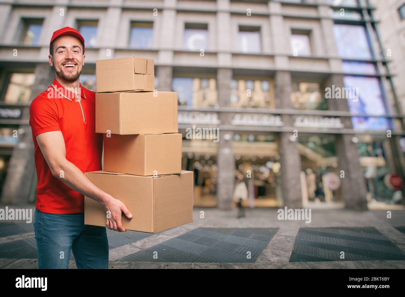 Red courier outside carries parcels for deliveries of shipments Stock ...