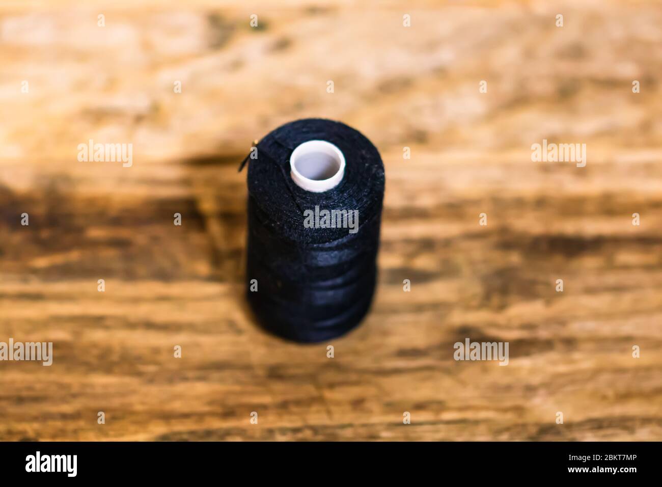 Black spool of sewing threads isolated on blurred background Stock ...