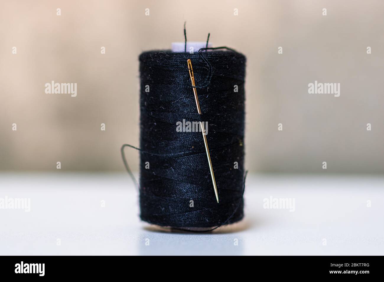 Black spool of sewing threads isolated on blurred background Stock ...