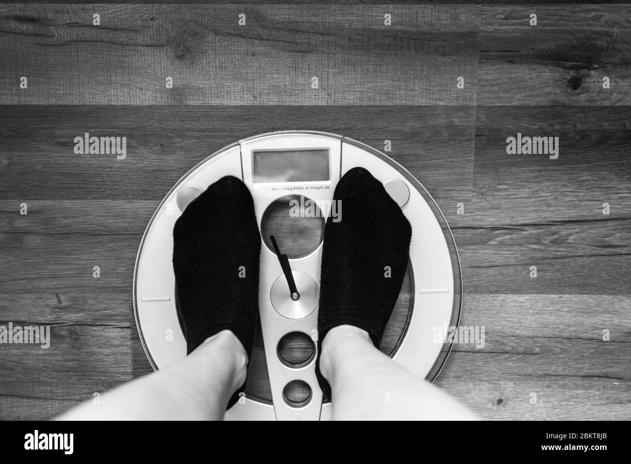 Person standing on a weight scale at home. Feets on weight scale with ...