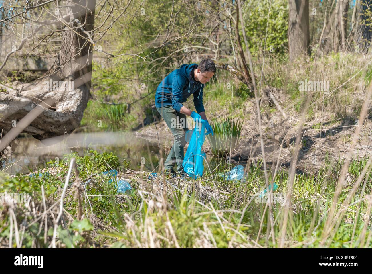cleaning of plastic waste on the river bank by a volunteer. Helping ...