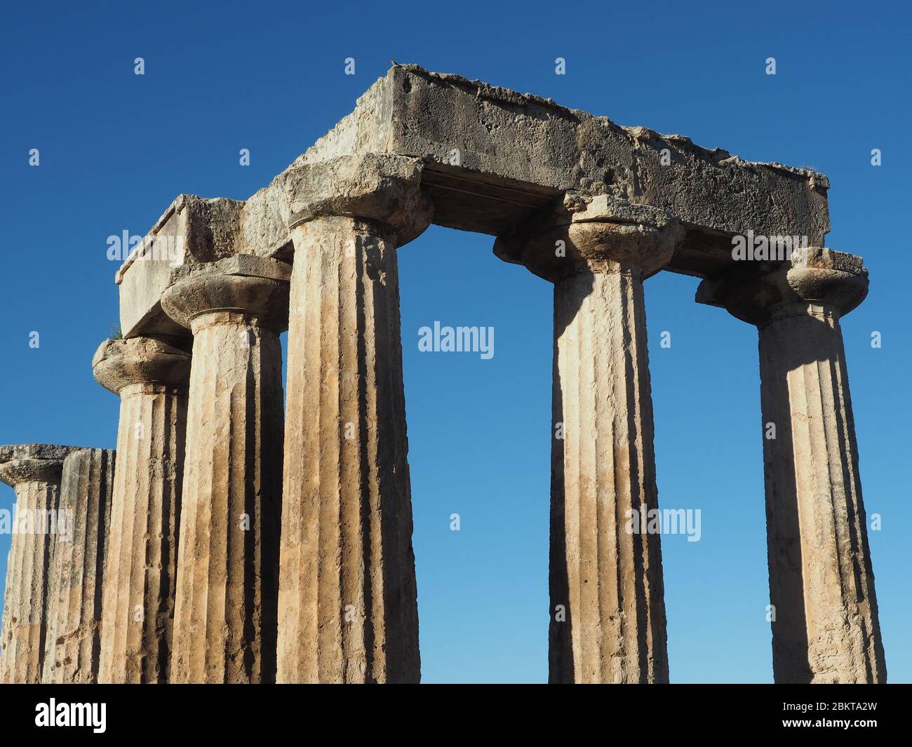 Doric columns of the Archaic Temple to Apollo in Corinth, Peloponnese, Greece against a blue sky ...
