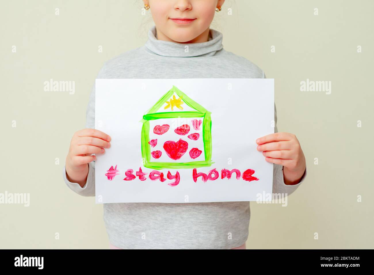 Child is holding a picture of house with hearts and words Stay Home on ...