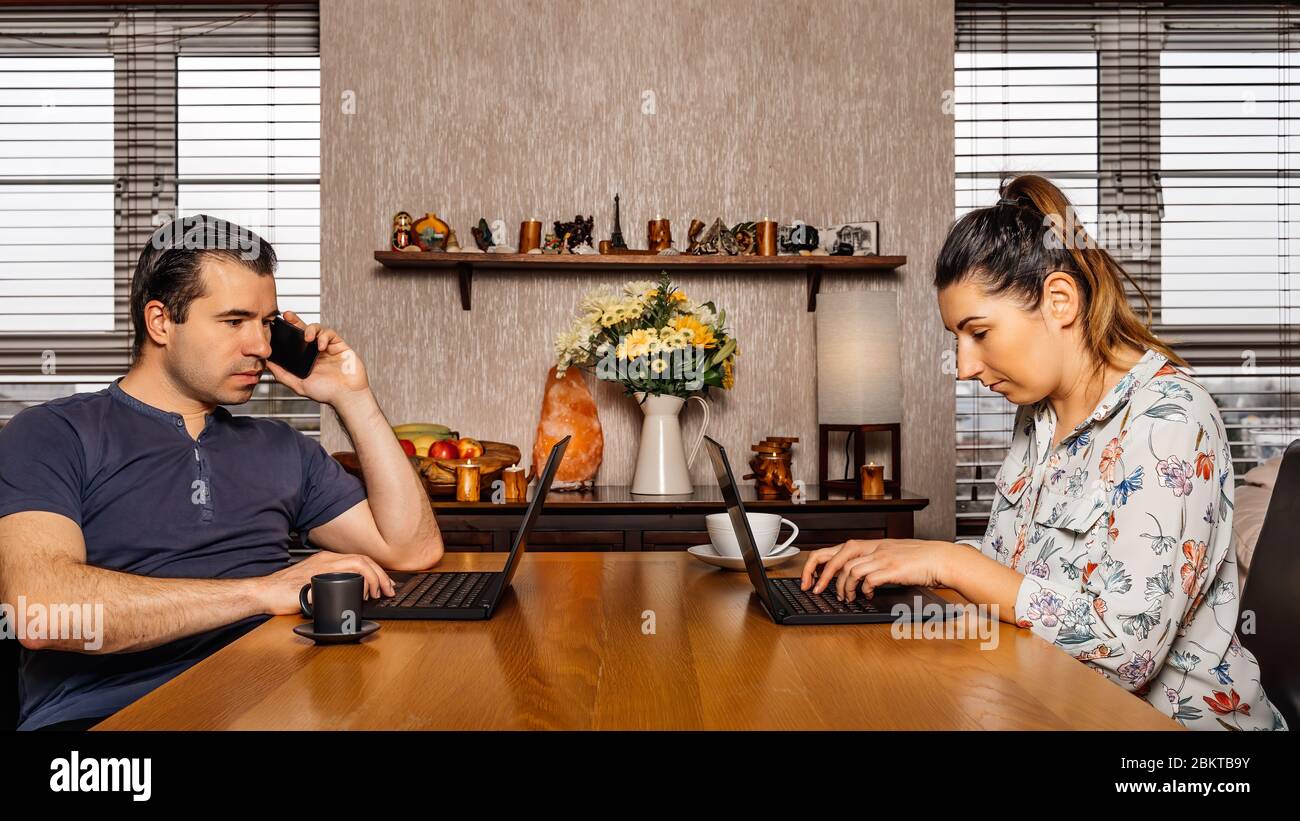 Men and woman, couple, talking and working on computers from comfort of ...