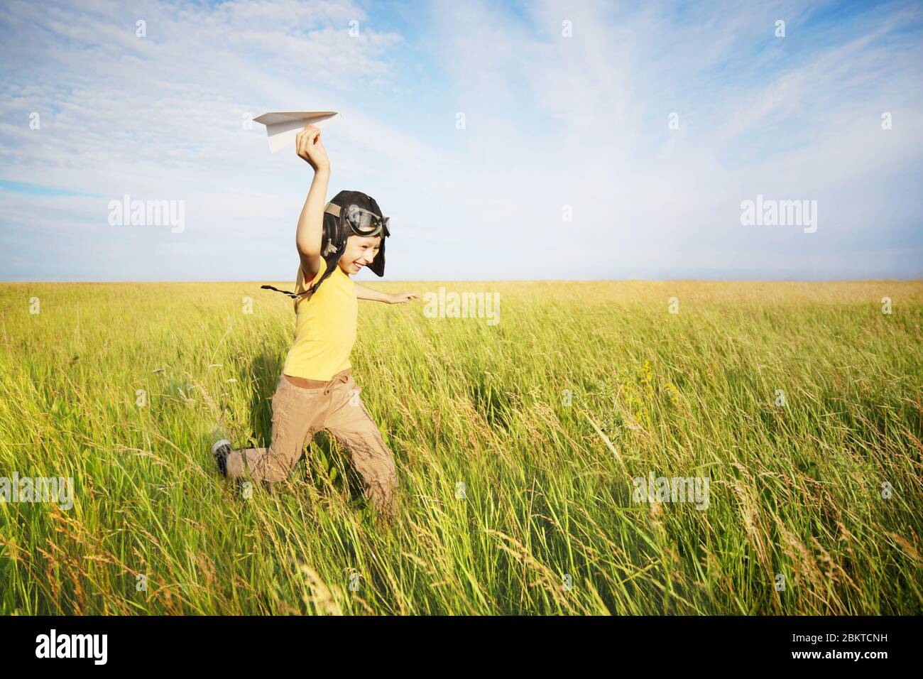 Young boy dressed as pilot running on field with Paper Airplane Stock ...
