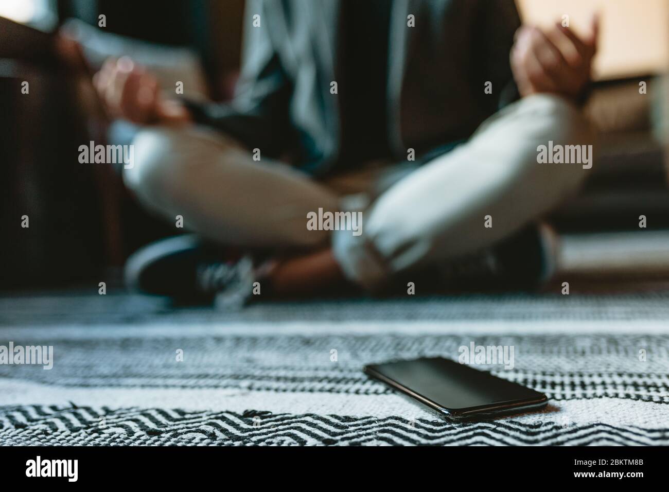 Mobile phone on floor with a businessman meditating in yoga pose in ...