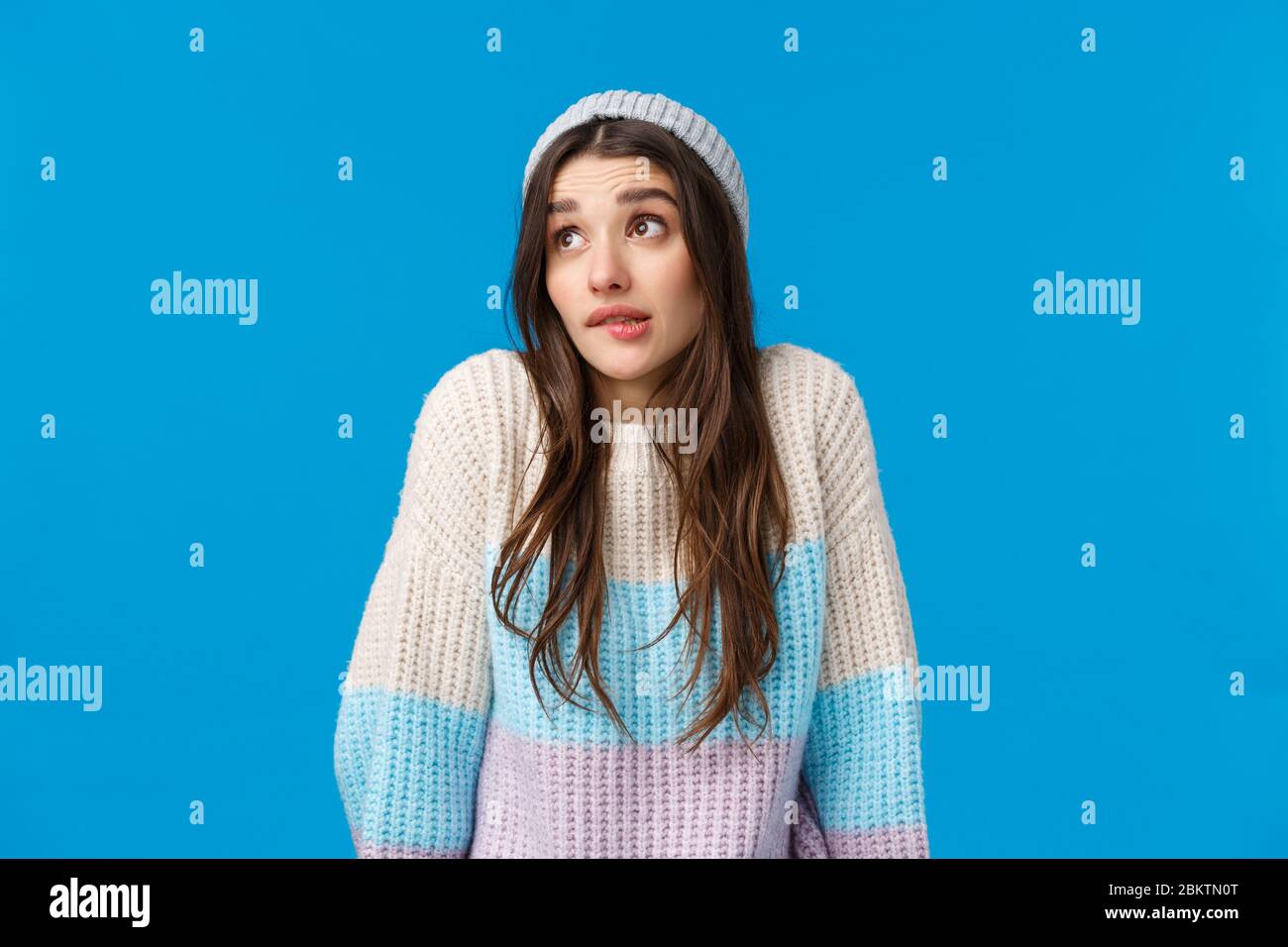 Silly and cute awkward young woman acting uninvolved, biting lip ...