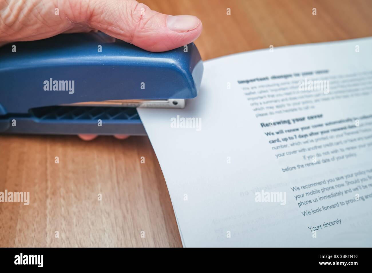 9 Close up of human hand stapling together sheets of paper with a blue ...