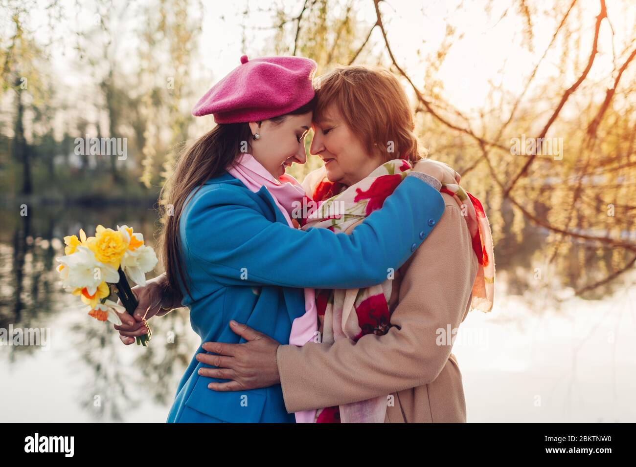 Mother's day. Senior mother with gifted flowers and her adult daughter ...