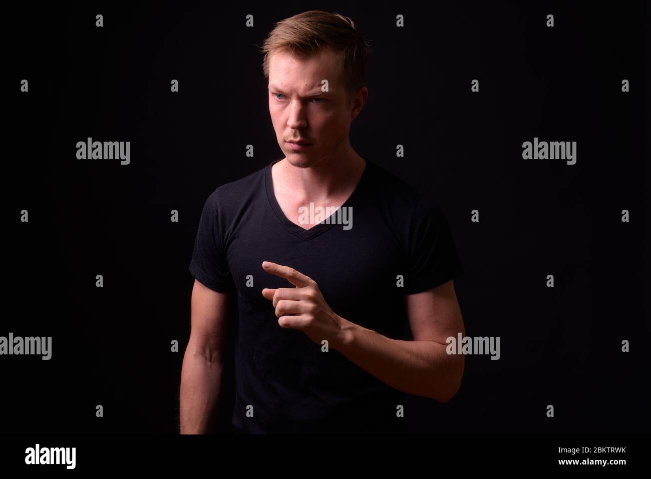 Portrait of stressed young man thinking and pointing finger Stock Photo ...