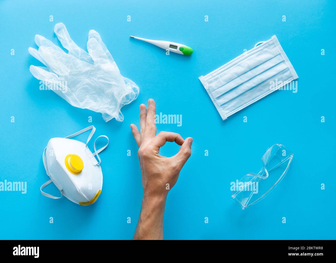 Man's hand showing ok sign with a medical protective mask, respirator ...