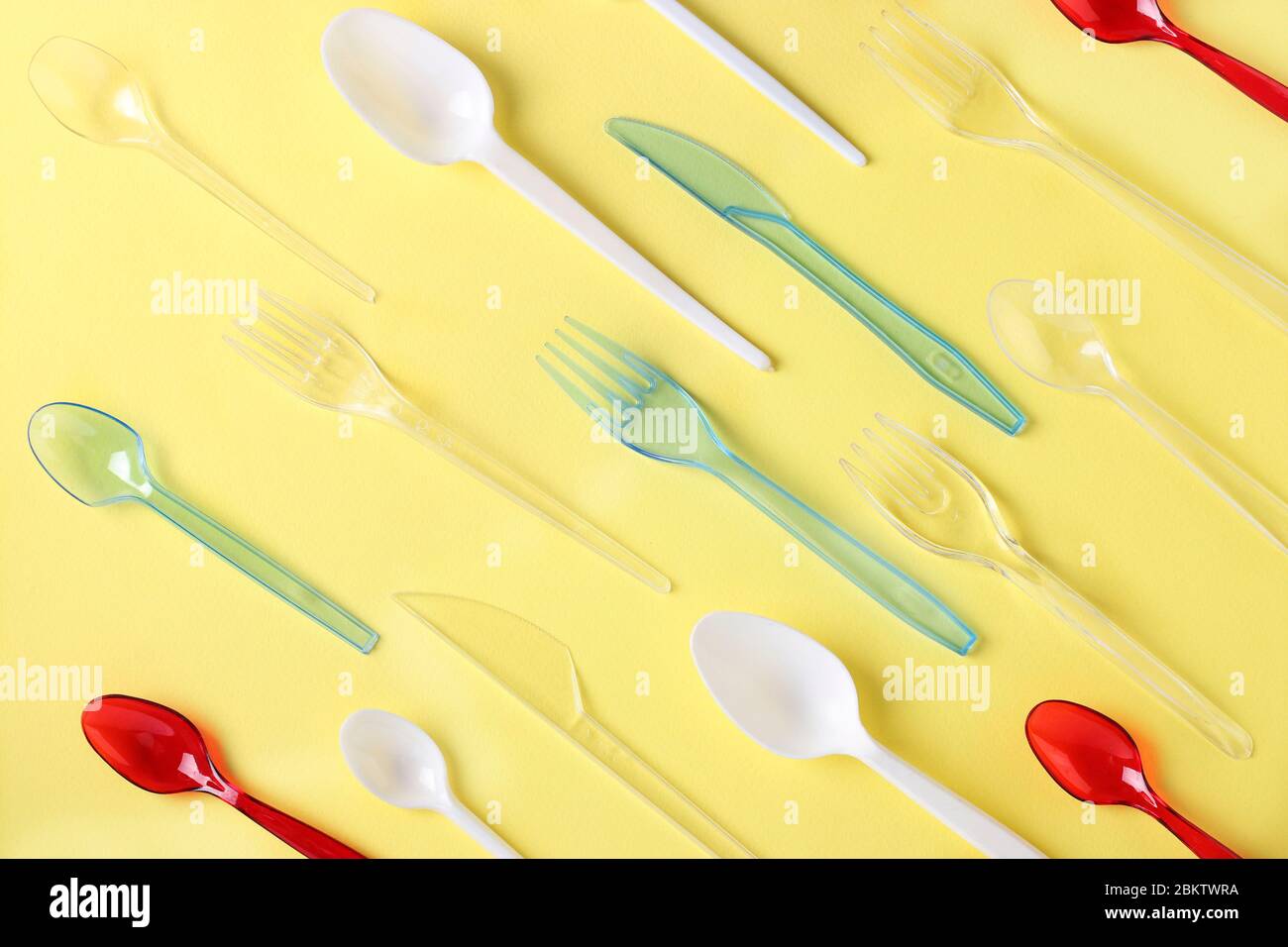 Pattern of a variety of plastic cutlery on a yellow background ...