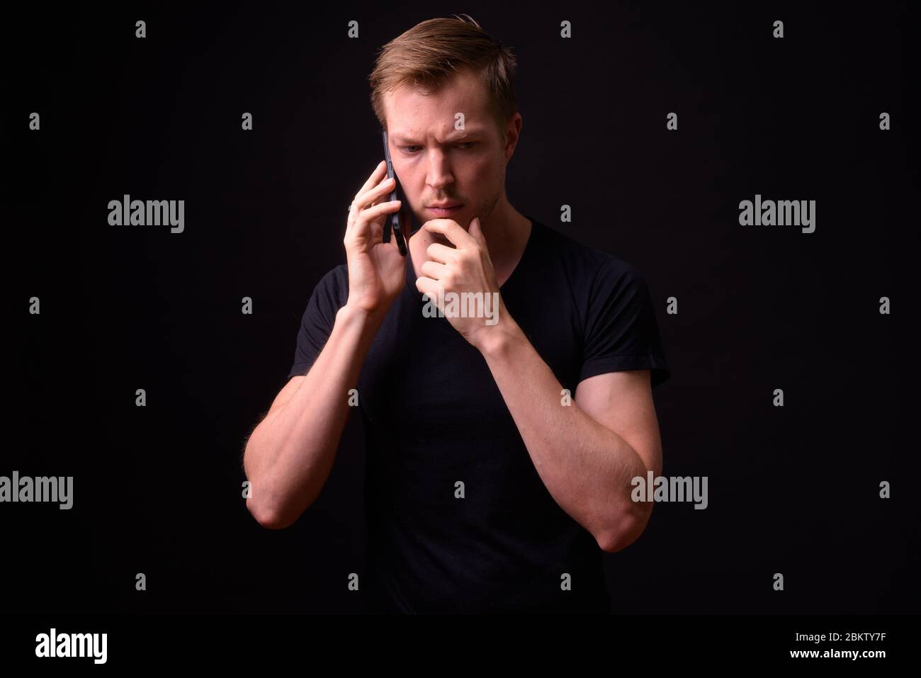 Stressed young man thinking while talking on the phone Stock Photo - Alamy