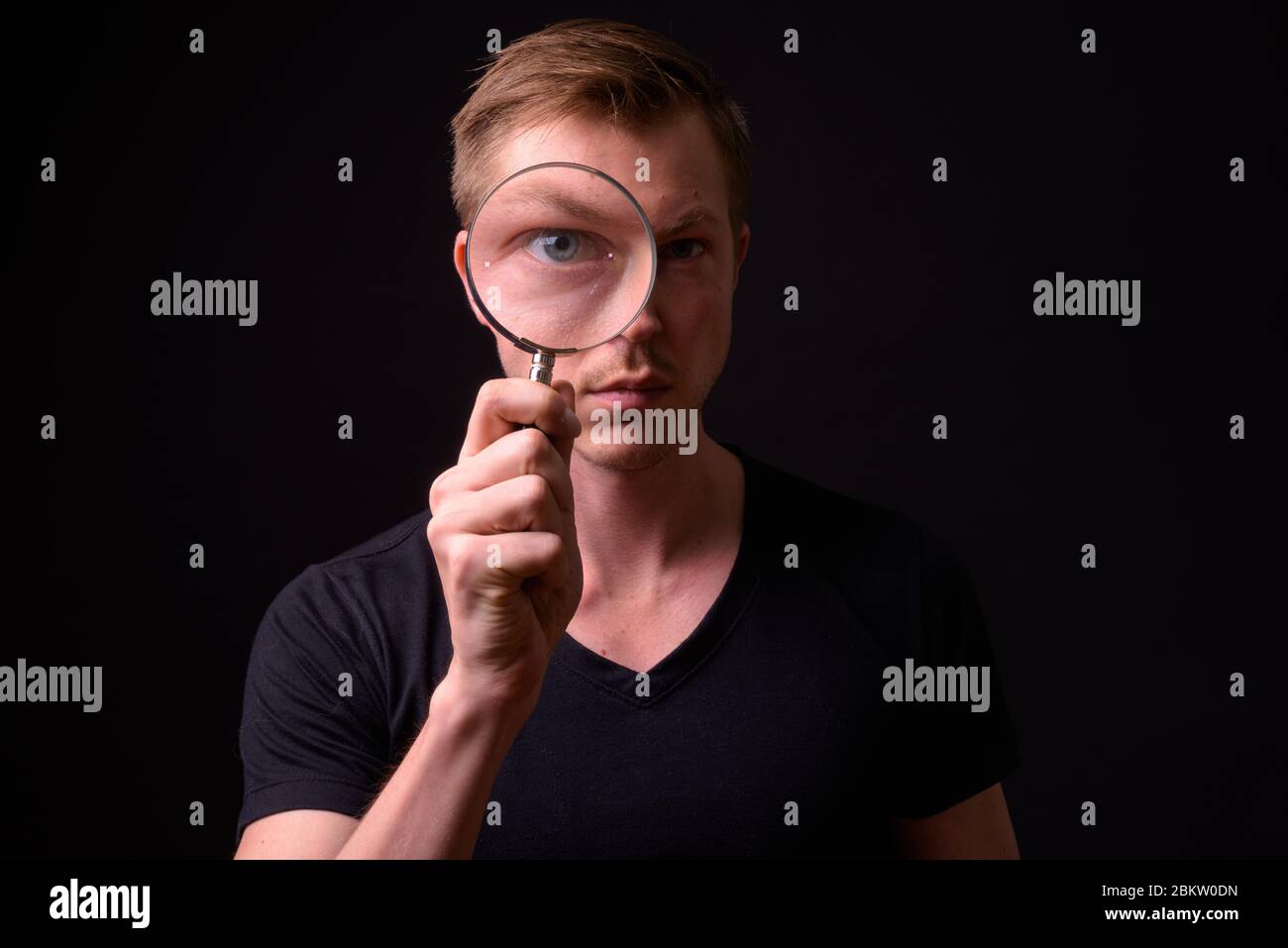Face of young handsome man using magnifying glass Stock Photo - Alamy