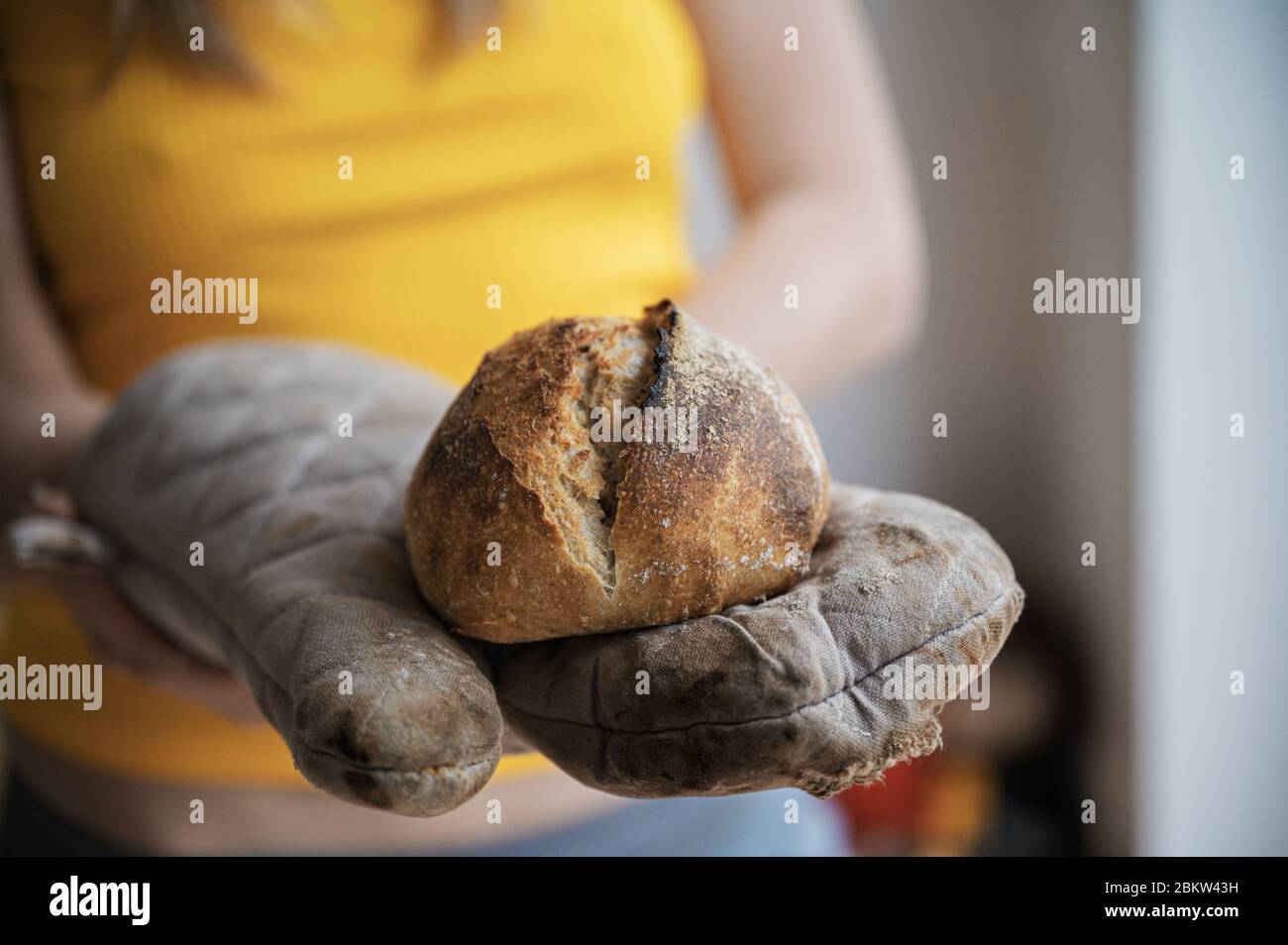 Closeup view of a woman wearing kitchen mitten holding freshly baked ...