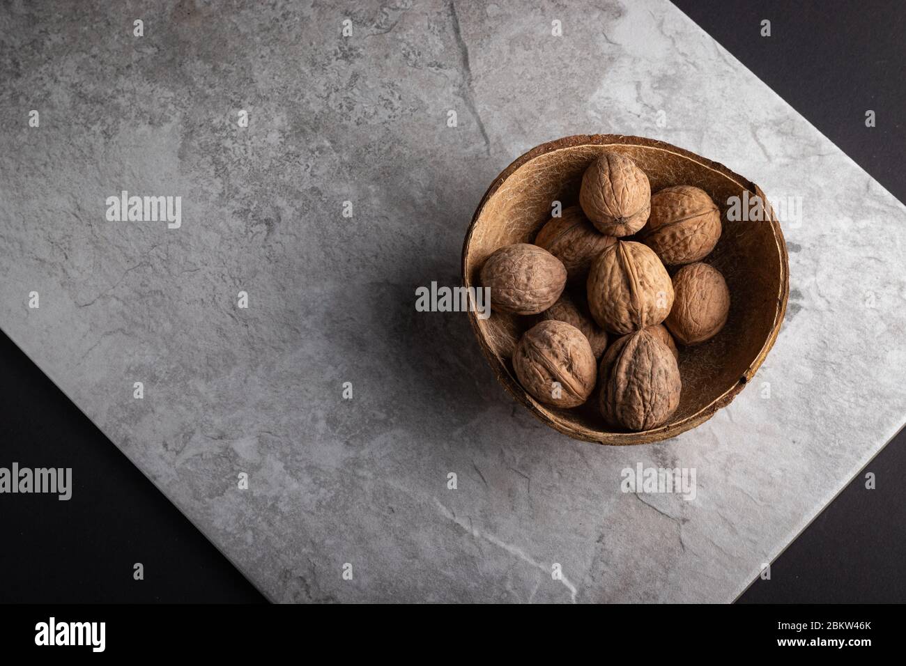 Walnuts inside a coconut shell on a tile background Stock Photo - Alamy