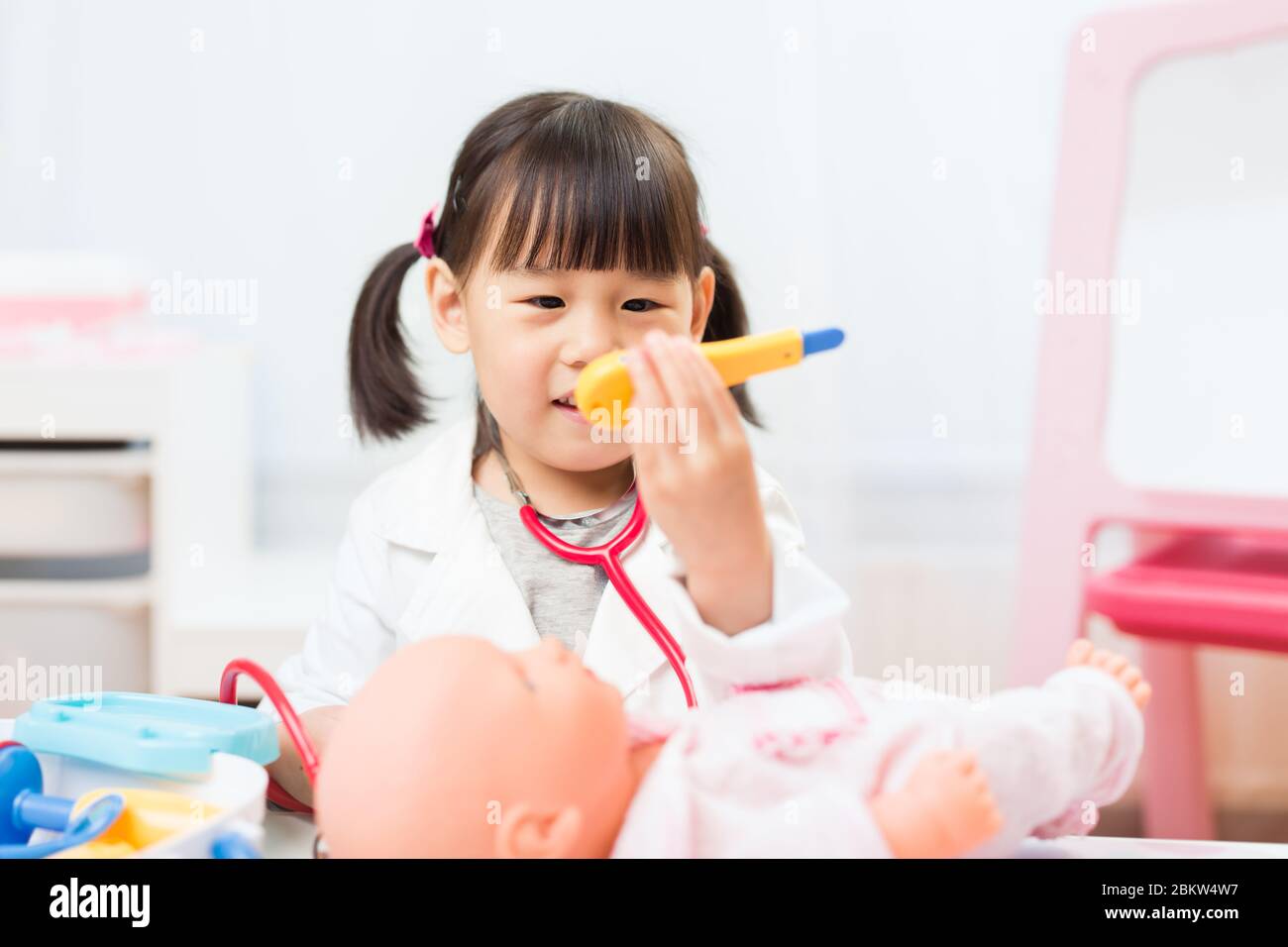 toddler girl pretend play doctor role at home against white background ...
