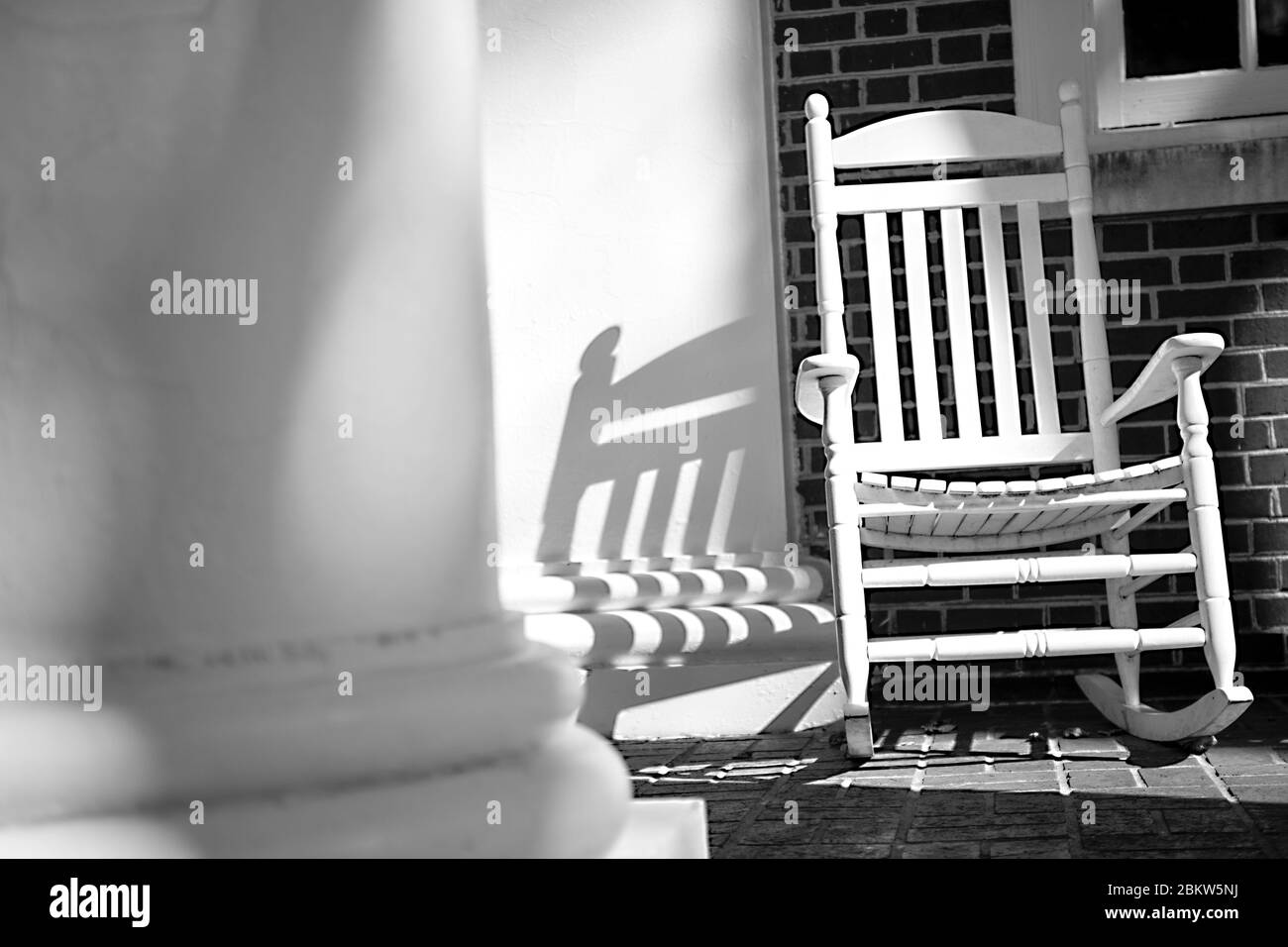 Rocking chair on dramatic empty front porch Stock Photo - Alamy