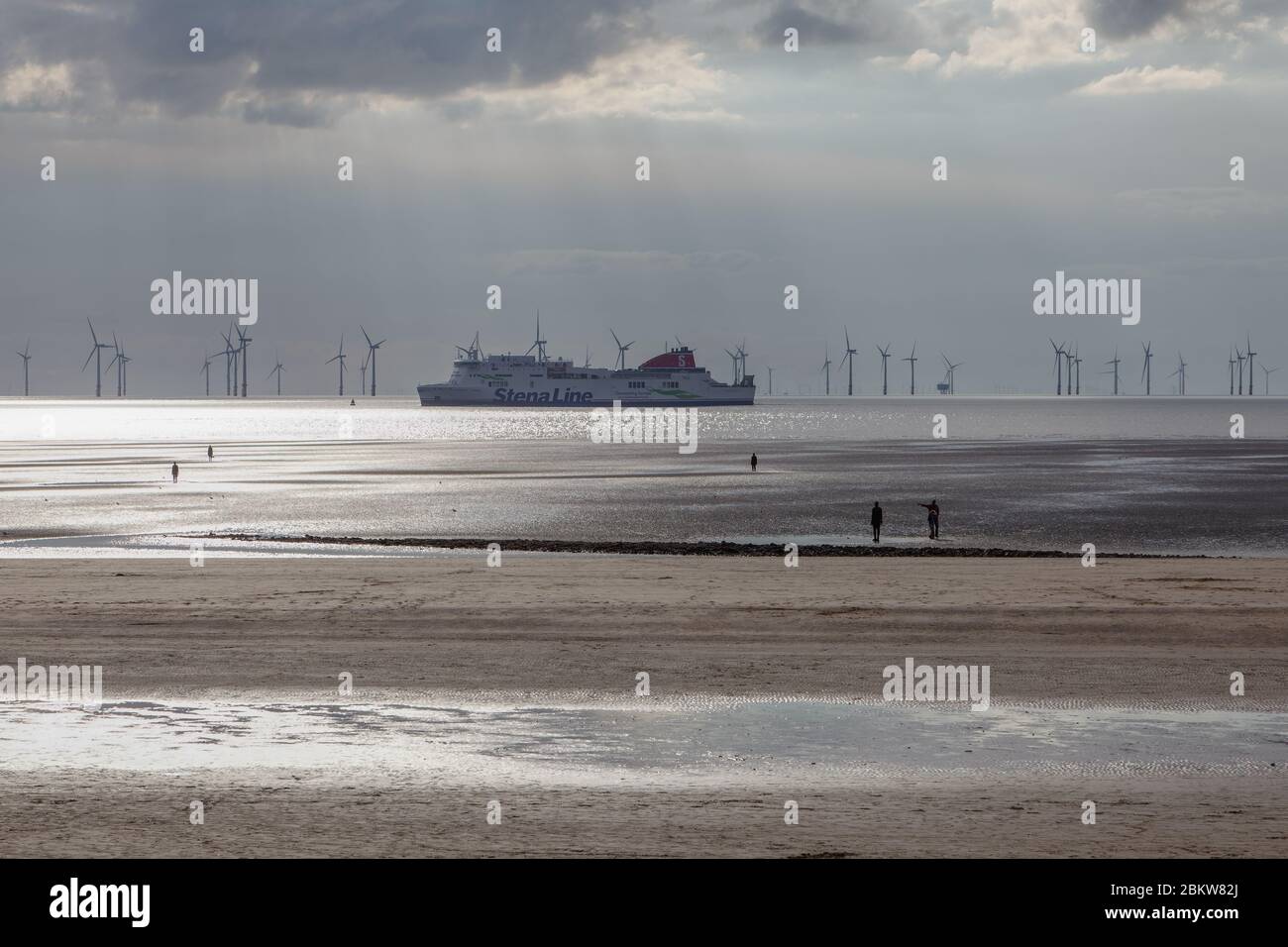 A ship passing the Another Place statues on Crosby Beach, which were ...