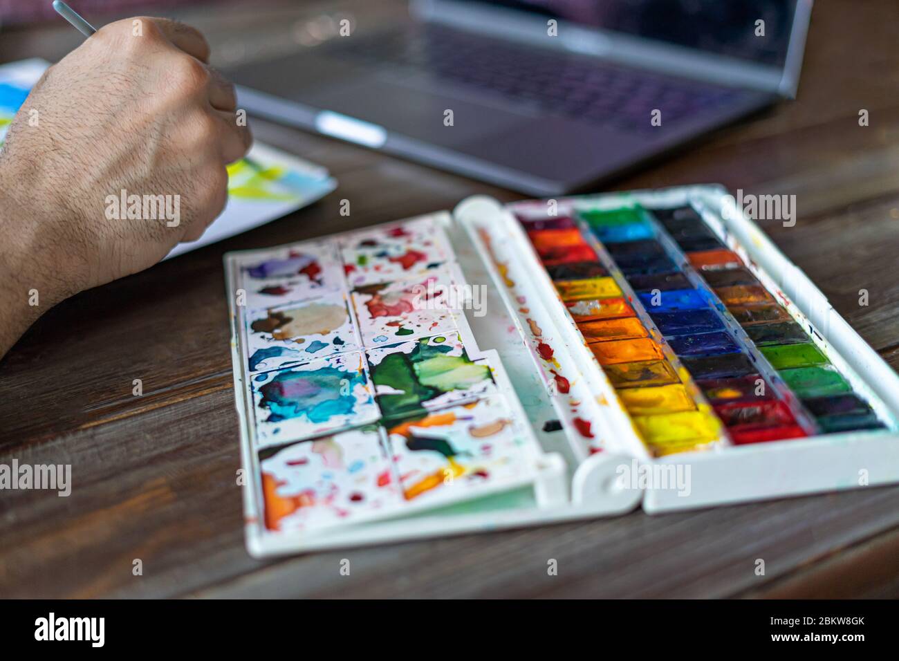 Painter artist using watercolor paints in front of laptop. online ...