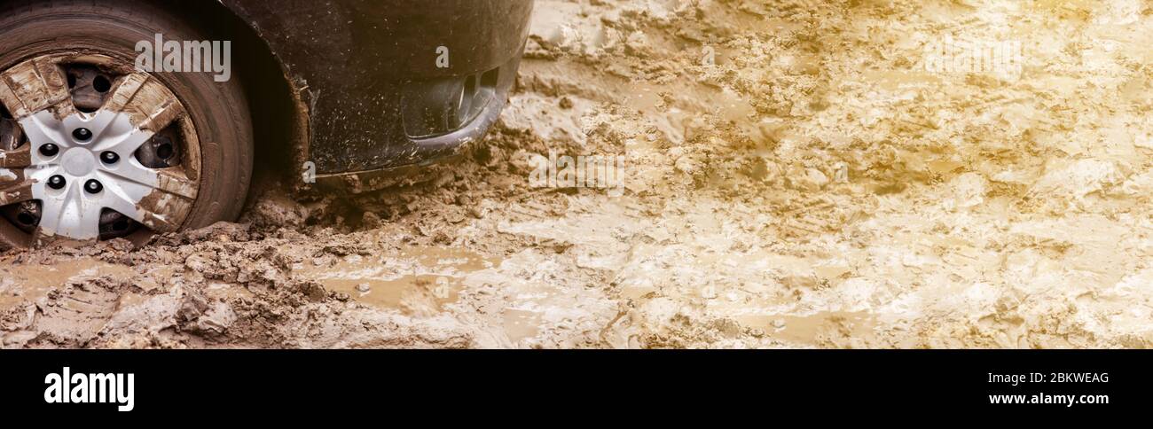 The car got stuck on a dirt road in the mud. Wheel of a car stuck in ...