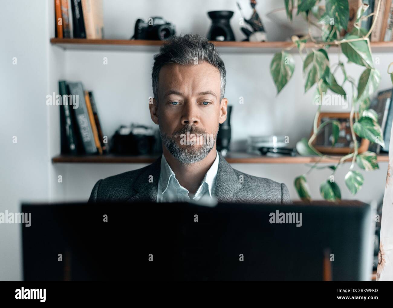 Portait of serious looking business man working on computer in the home ...