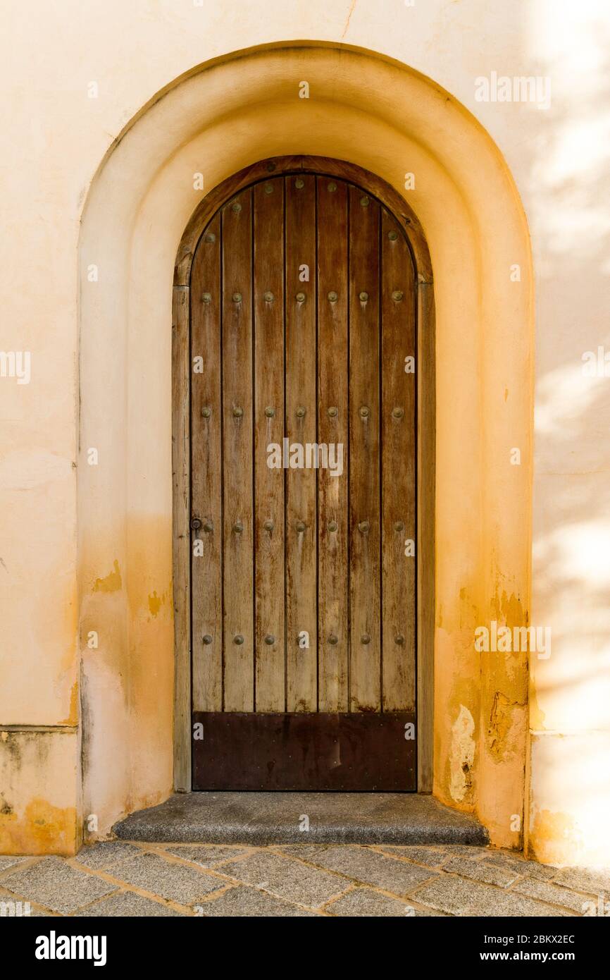AN old spanish wooden door in a golden stucco archway Stock Photo - Alamy