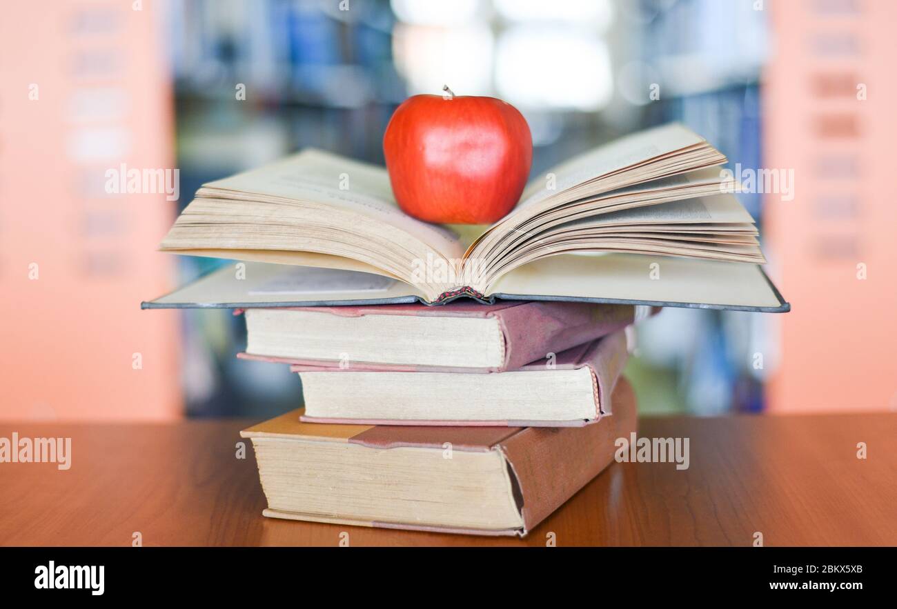 An apple on the books on the table with bookshelf in the library ...