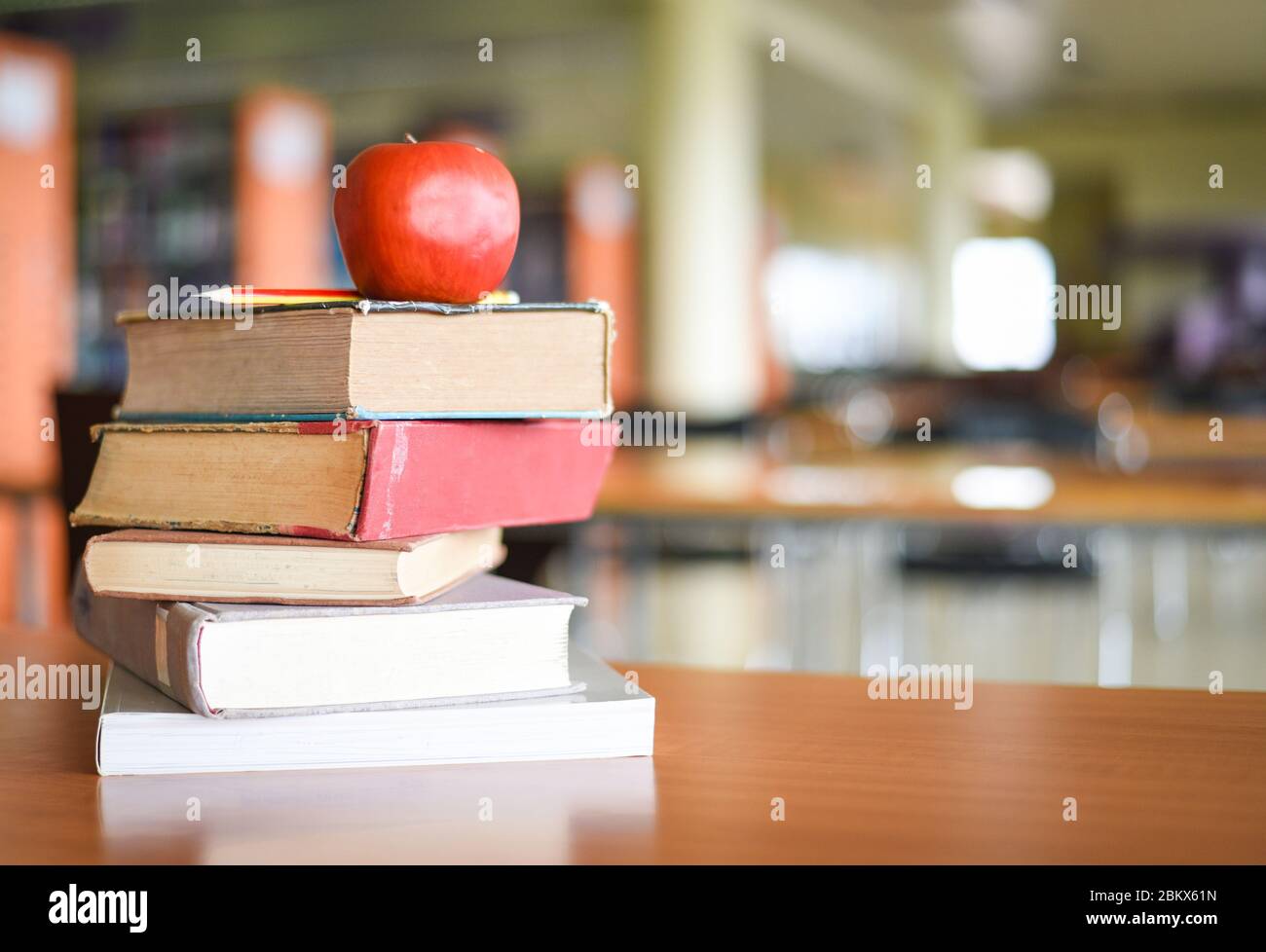 An apple on the books on the table with bookshelf in the library ...