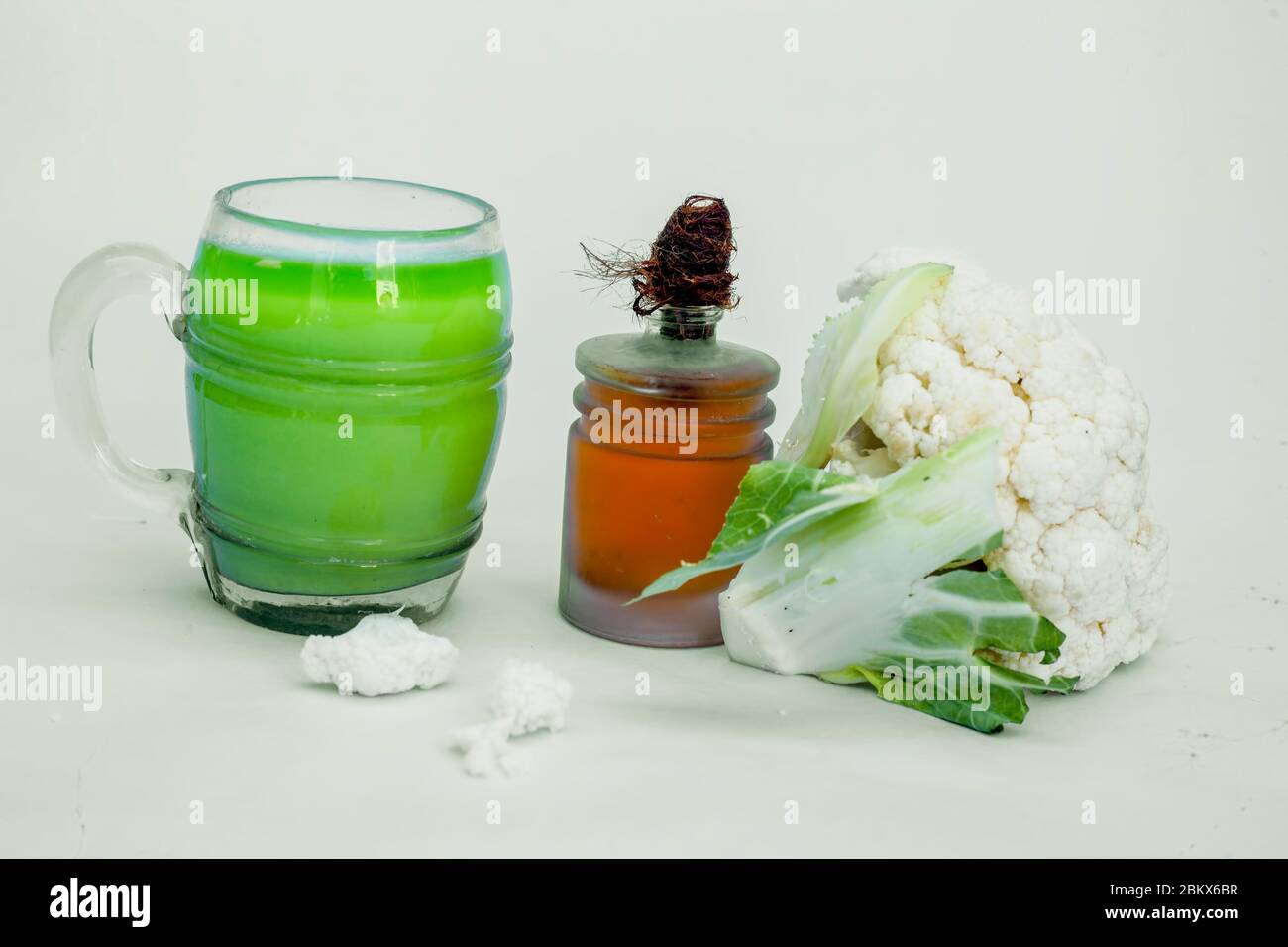 Shot of fresh cauliflower along with its juice and oil on off white ...