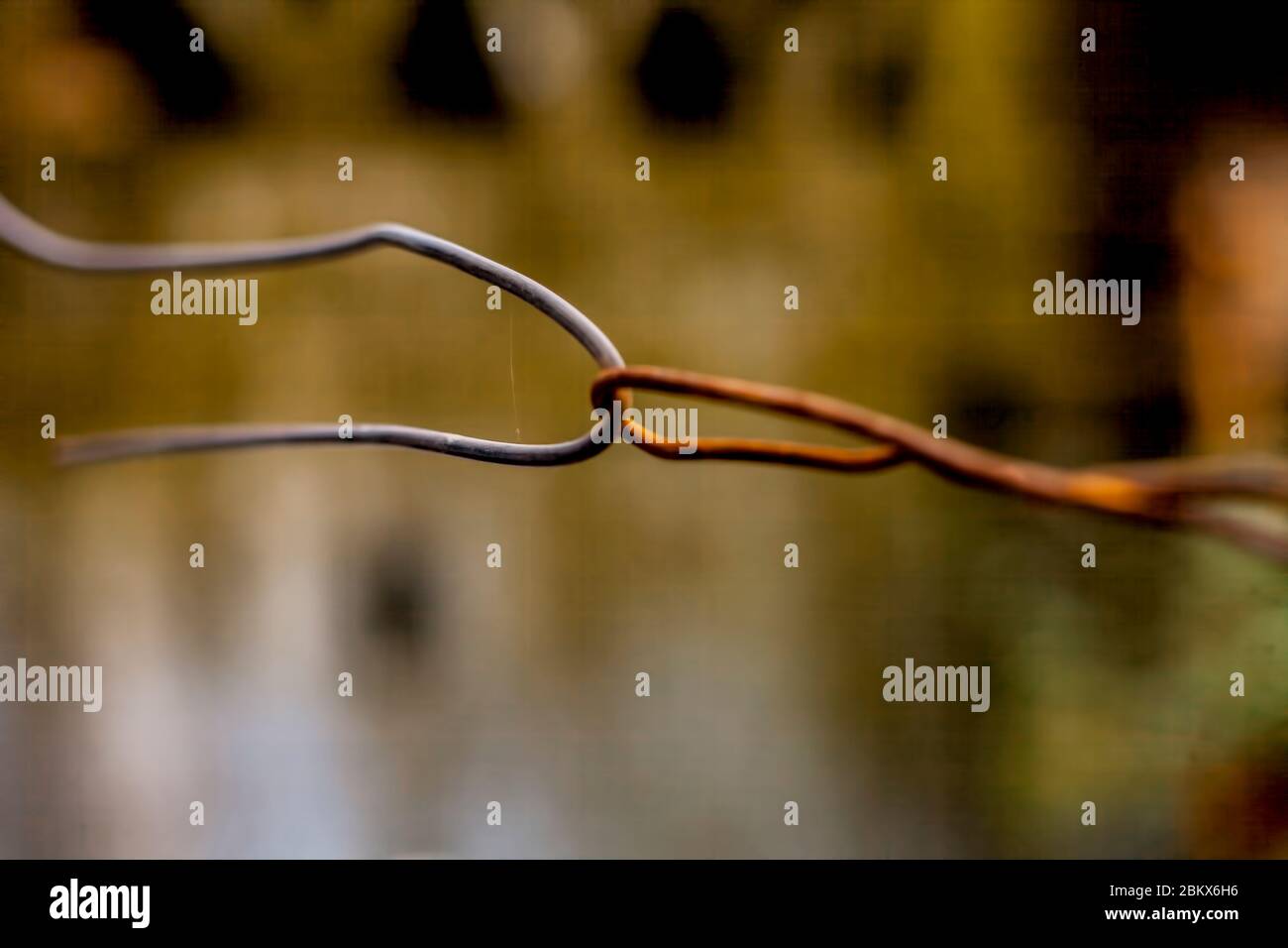 Shot of rusted metal wire joined with another by bending with blurred ...