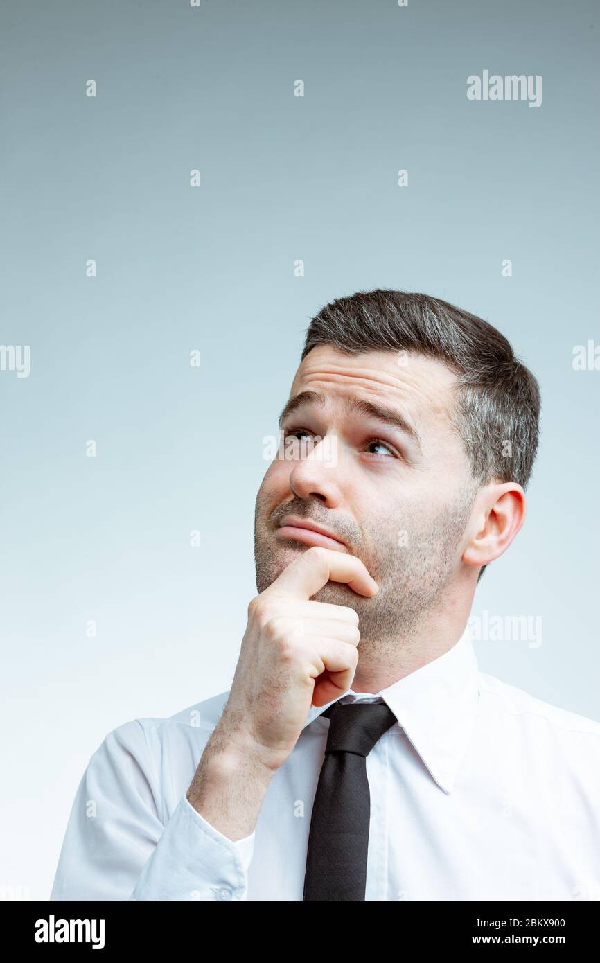 Handsome young man in white shirt and black tie, holding hand to his ...