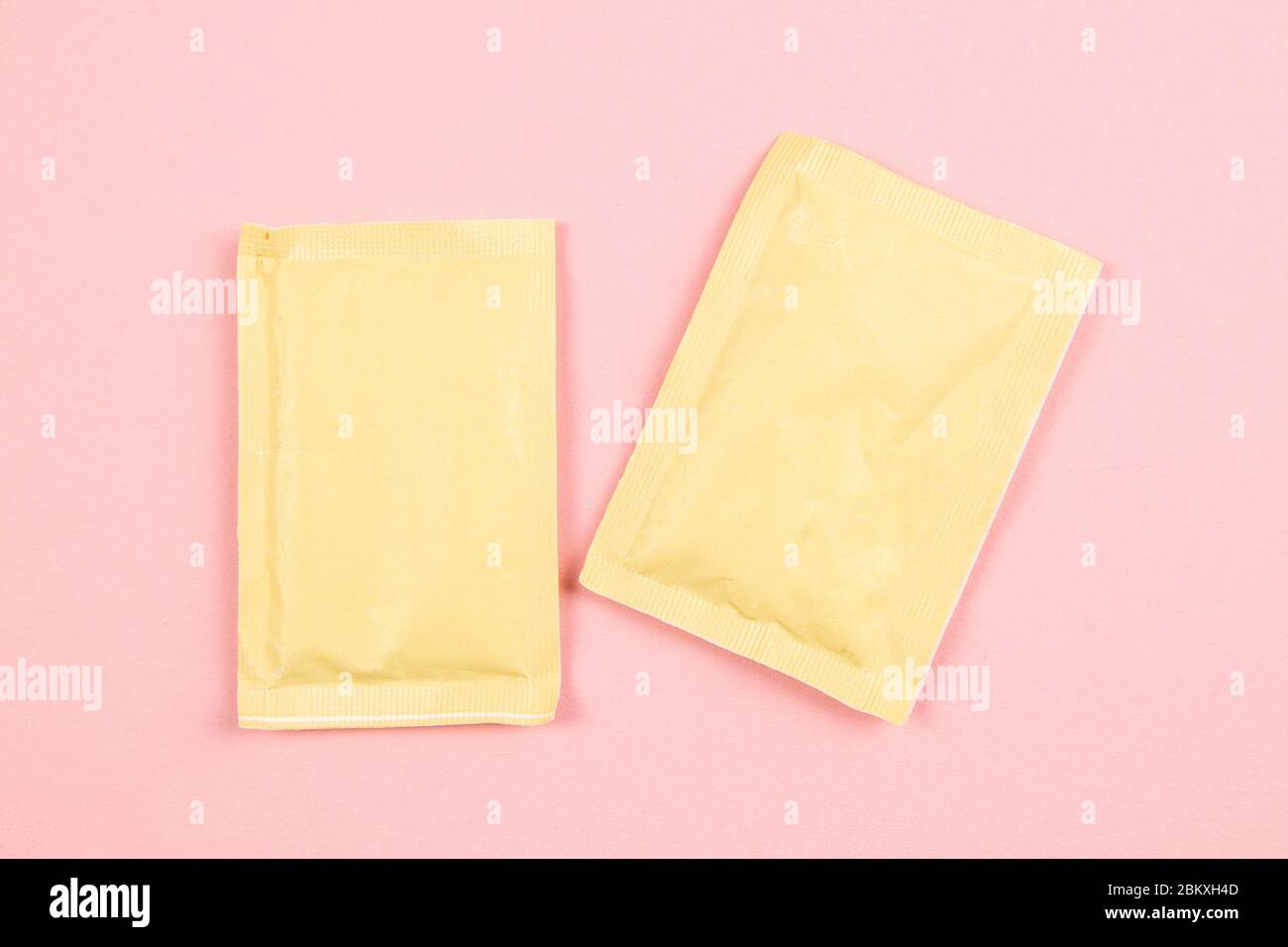 Two white paper sachets isolated on pink background. Top views with ...