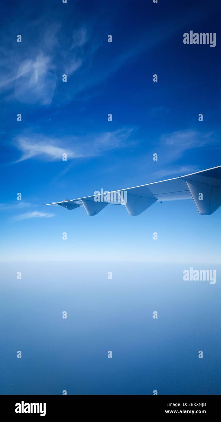 Plane wing against the beautiful blue sky and clouds and ocean from the ...