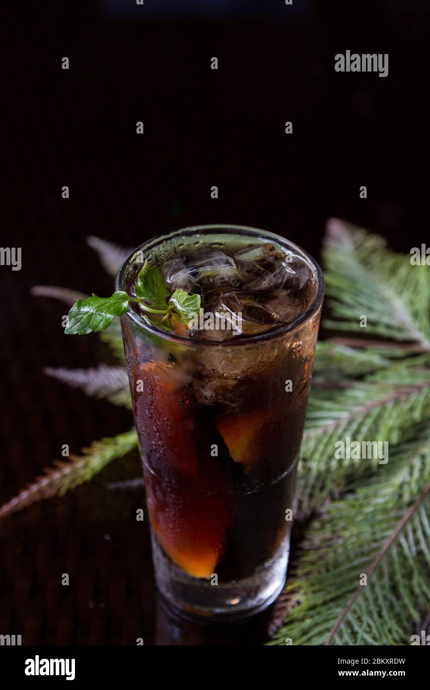 Long island cocktail drink with decorative plant on black background ...