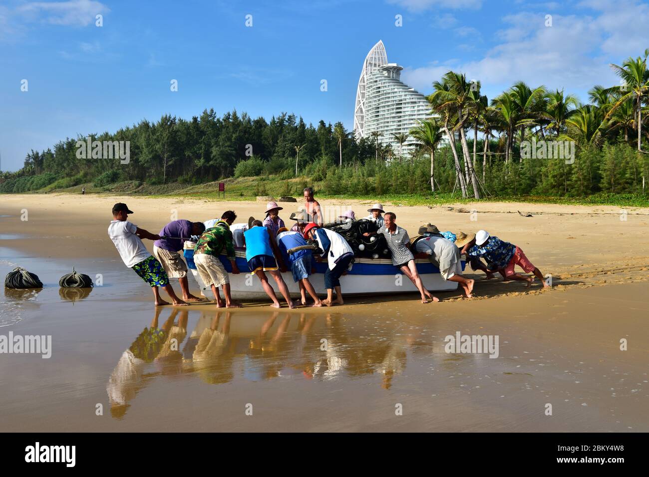 People pushing fishing boat together Stock Photo - Alamy