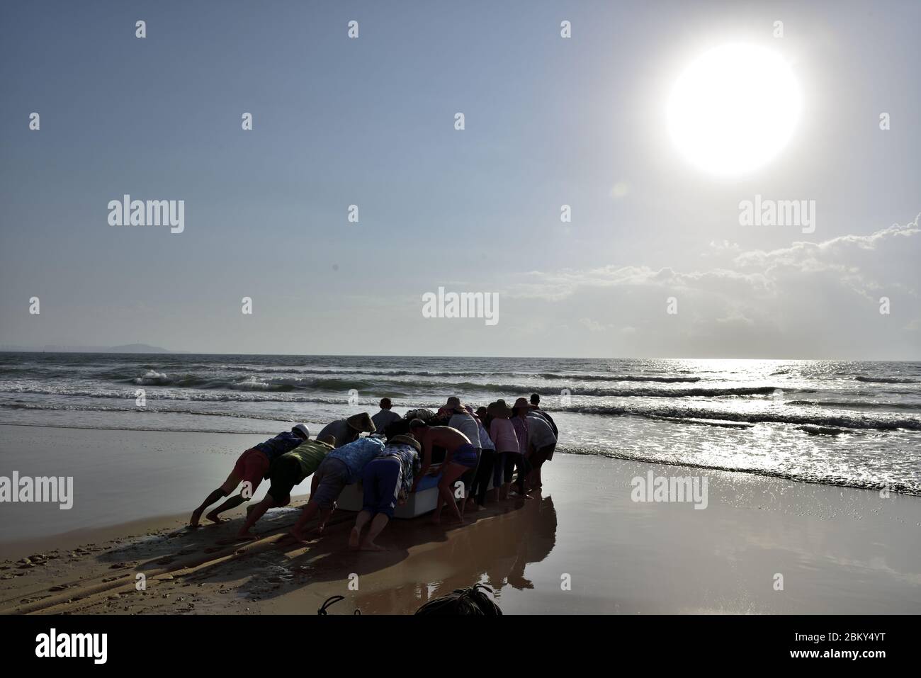 People pushing fishing boat together Stock Photo - Alamy