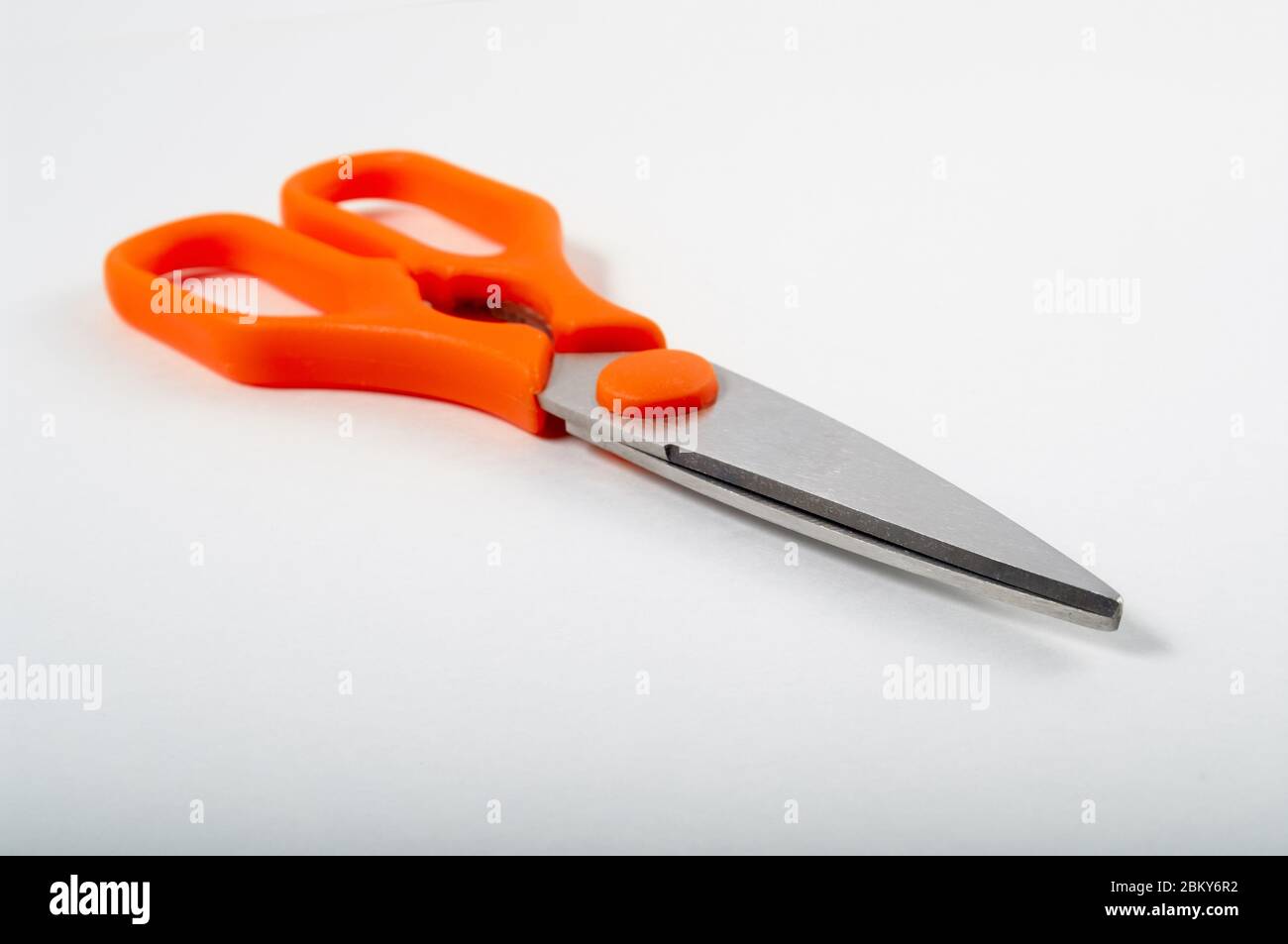 Steel modern kitchen scissors with orange plastic handles isolated on a ...