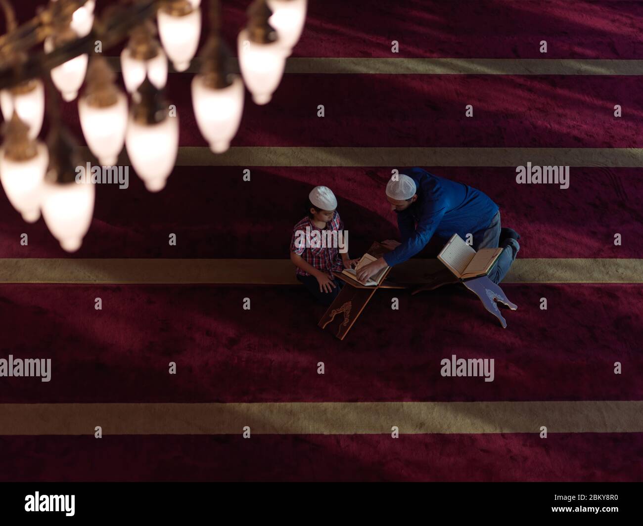 muslim prayer father and son in mosque praying and reading holly book ...