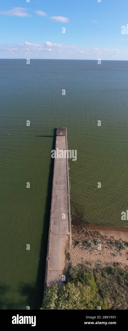 Long concrete pier breakwater on sea lagoon, aerial view, vertical pano ...