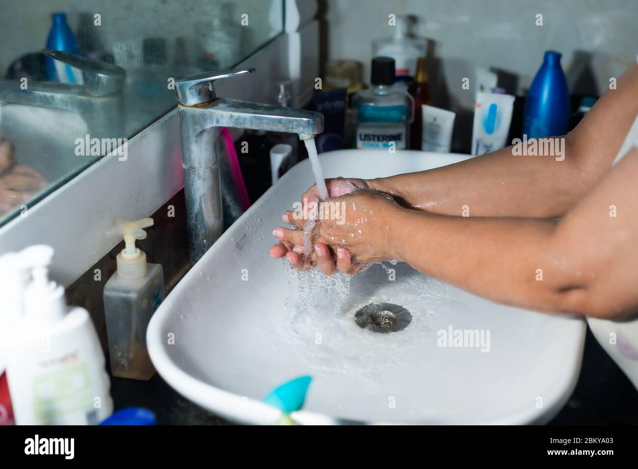 Adult washing hands and arms properly with alcohol soap under the sink ...