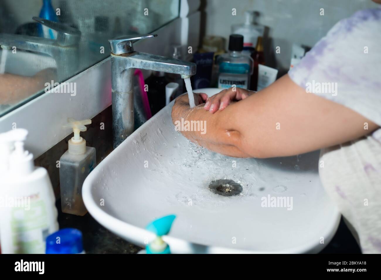 Adult washing hands and arms properly with alcohol soap under the sink ...