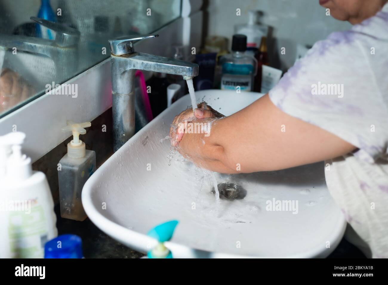 Adult washing hands and arms properly with alcohol soap under the sink ...