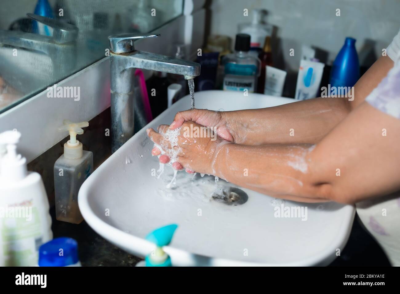 Adult washing hands and arms properly with alcohol soap under the sink ...